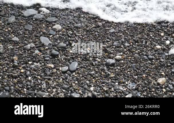 Small gentle waves splashing to pebble beach at sunny day. Ocean tides ...