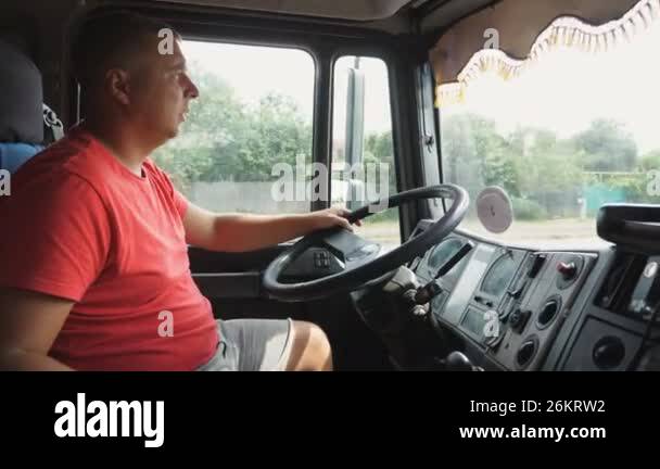 Lorry driver holds hand on a steering wheel and controls car riding to ...