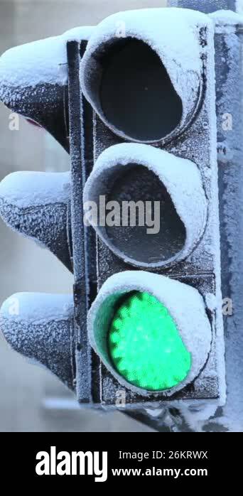A traffic light covered in snow and ice on a cold winter day. Harsh ...