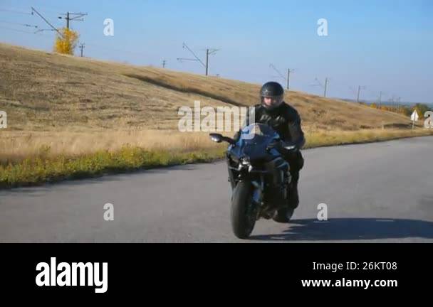 Young man riding on modern sport motorbike at autumn highway ...