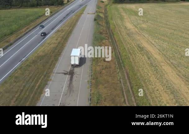 Aerial view of truck with cargo trailer driving on straight road and ...