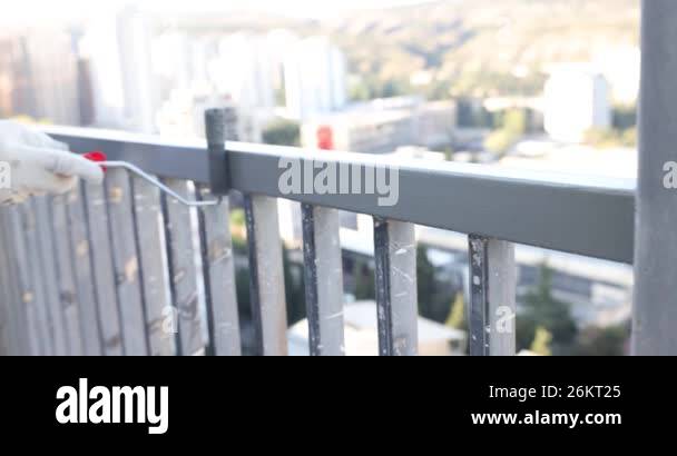 Painting balcony railings in a high rise building with a view of city ...