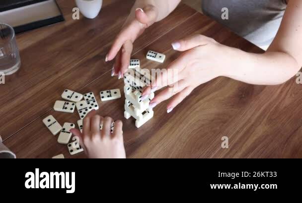 Build a domino tower at home with your family. Mom and daughter engage ...
