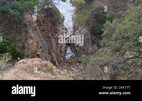 A dramatic mountain gorge showcases a cascading stream cutting through ...