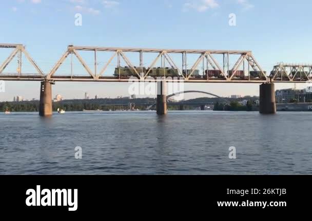 Freight train moving on a railway bridge over a river. View from a ...