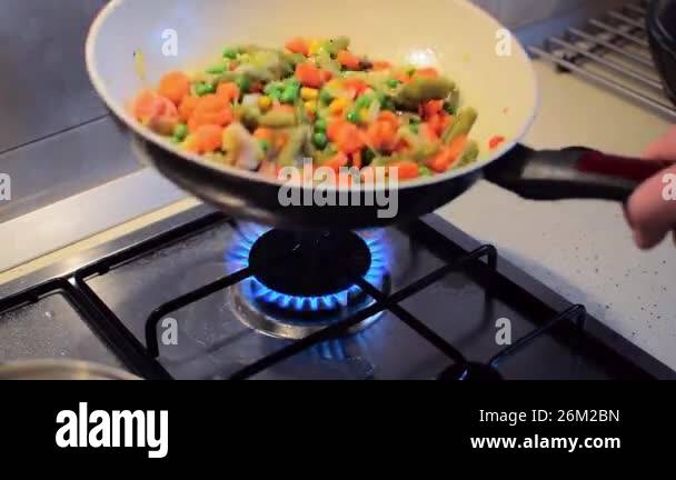 Mixed vegetables in frying pan cooking, vegetarian meal being prepared ...