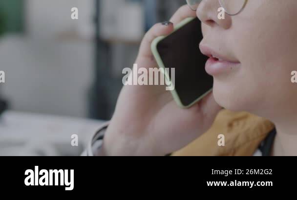 Close-up of woman speaking on mobile phone holding wireless ...