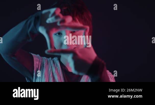 Portrait of Asian woman making viewfinder hand gesture looking at ...