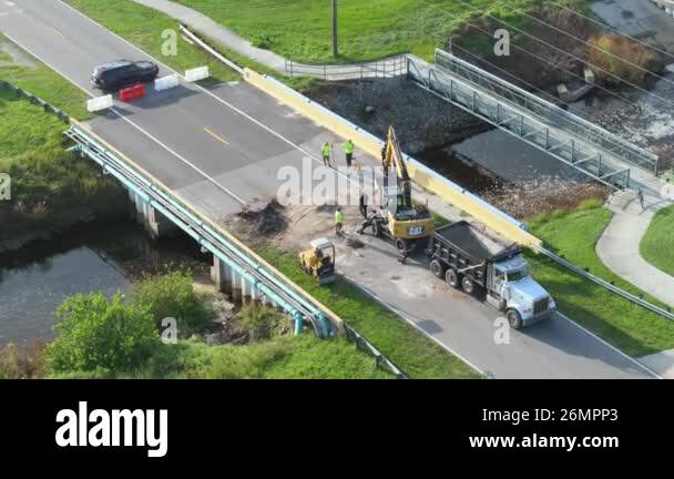 Road construction. Workers repairing destroyed bridge after hurricane ...