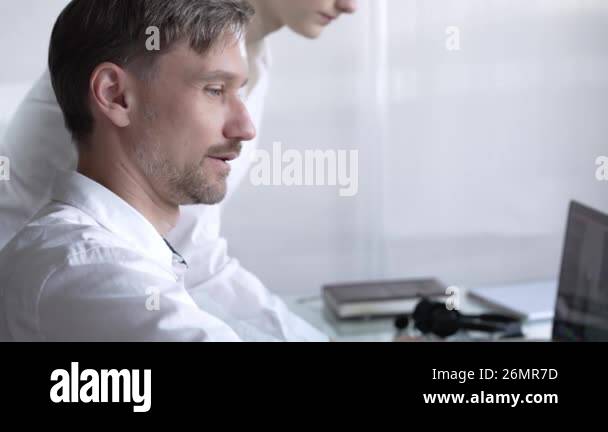 Business colleagues collaborating on a project, reviewing data on a laptop and engaging in ...