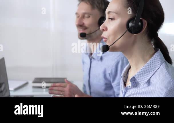Focused female call center operator in blue casual blouse is assisting clients online, providing ...