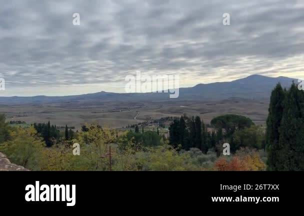 Idyllic view of the Tuscan countryside featuring rolling hills, autumn foliage and distant ...