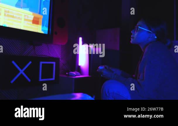 A woman is playing a video game on a Playstation 4. She is wearing ...