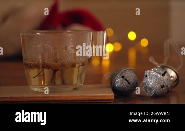 Cup of chamomile tea with Christmas baubles with twinkling lights background bokeh close up zoom ...