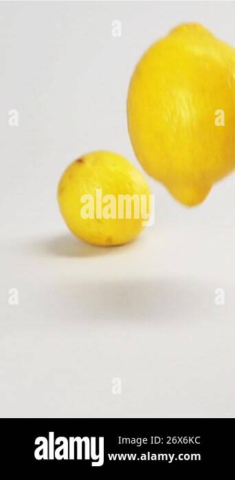 Few fresh tasty yellow lemons in white screen bg falling down at gray ...