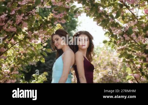 Twin models standing gracefully amidst vibrant sakura blossoms, dressed ...