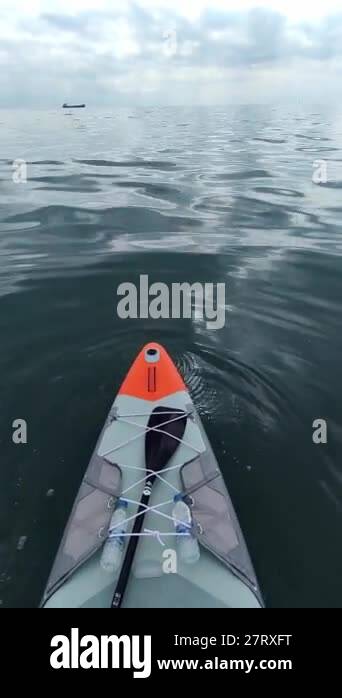 A stand-up paddleboard with paddles and water bottles, floating on calm ...