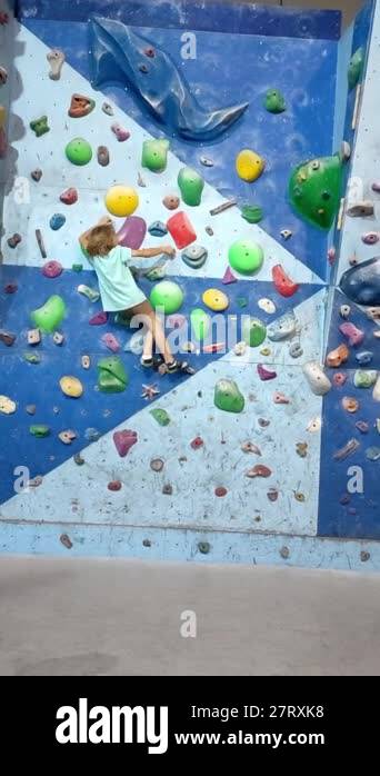 A child climbing a colorful indoor rock wall, showcasing strength ...