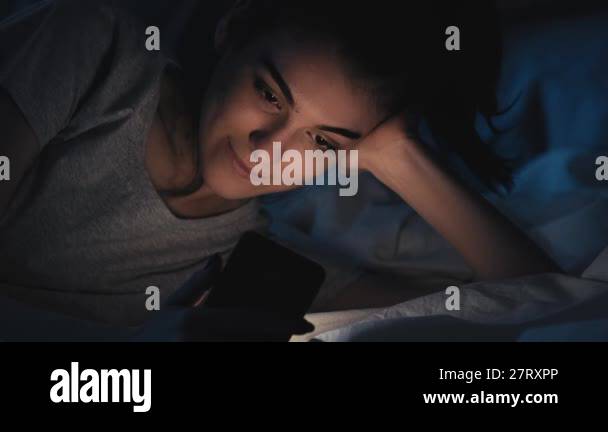 Mobile night. Gadget insomnia. Relaxed smiling woman enjoying using ...