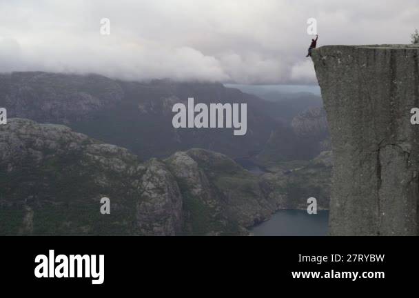 Adventurous Guy is sitting on the edge of Pierkestolen cliff in ...