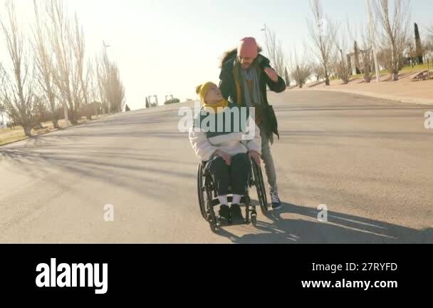 Supportive male companion walking alongside wheelchair using friend ...
