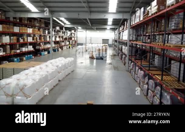 Large logistics warehouse features organized metal shelves filled with various products ...