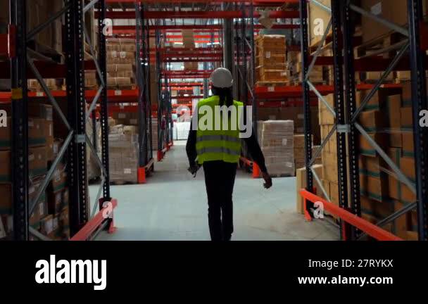 Logistics operator wearing a safety vest and helmet scans packages in a ...