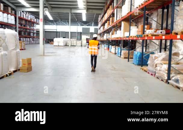 Logistics operator wearing an orange vest and white helmet walking ...