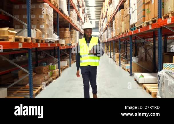 Logistics operator walking through warehouse aisles, checking goods and ...