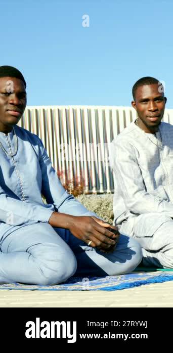 Two senegalese men wearing traditional dashiki clothing engage in a ...