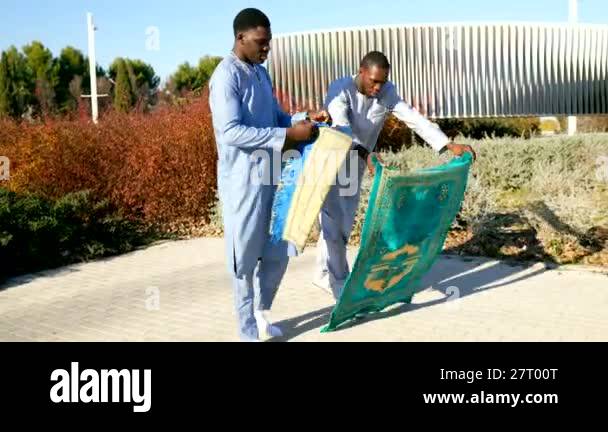 Two senegalese muslim men prepare prayer rugs and perform salat, the ...
