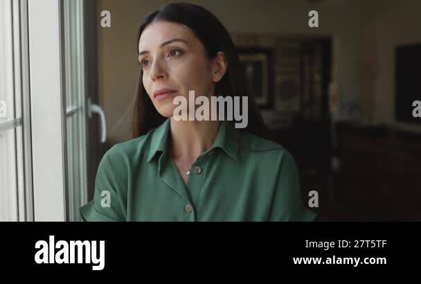 Close up of woman looks contemplative and melancholic gazing out of ...