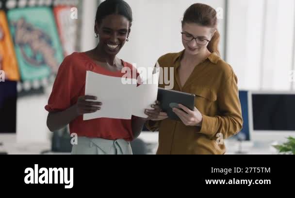 Two professional women holds set of documents and tablet engaged in ...