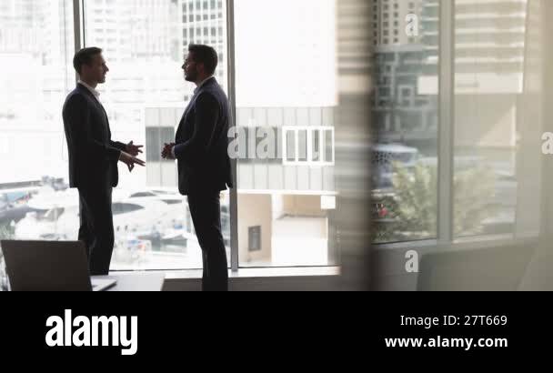 Hispanic and Arabian men colleagues talking standing against panoramic ...