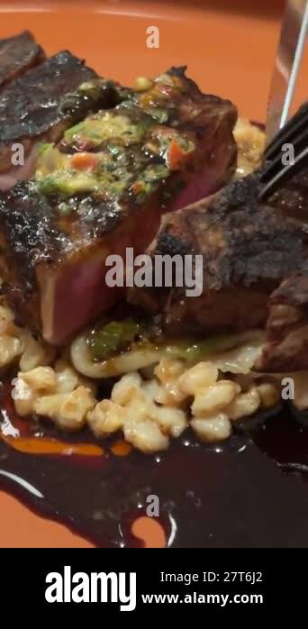 Chef slicing freshly grilled juicy beef steak meat with a knife on a ...