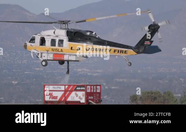 A Los Angeles County Fire helicopter skillfully hovers over the rugged ...