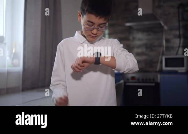 Young boy in eyeglasses checking notifications on smartwatch. Smart kid ...