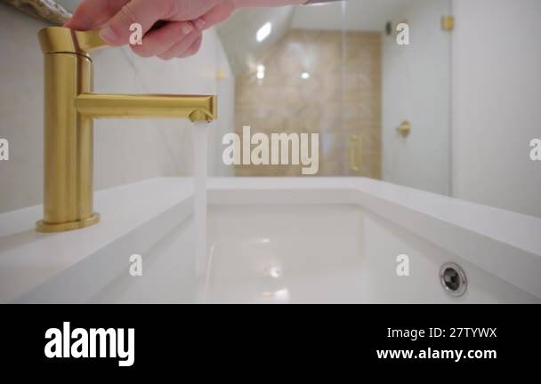 Man hand open and closed the golden water tap. White bathroom. Turning ...