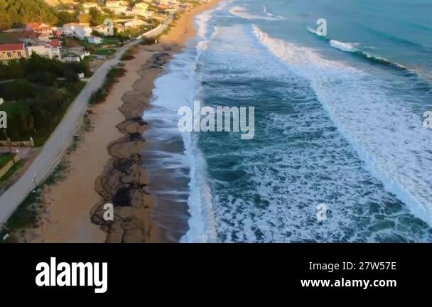Aerial view of ocean waves crashing on Agios Georgios Pagon beach in ...