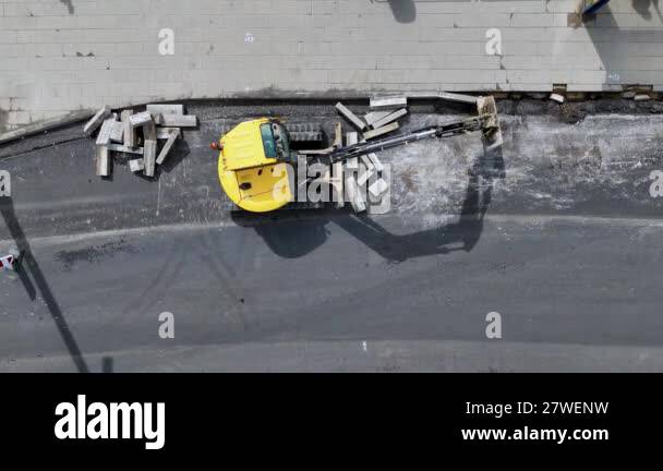 Aerial view of a yellow construction vehicle on a road removing old ...