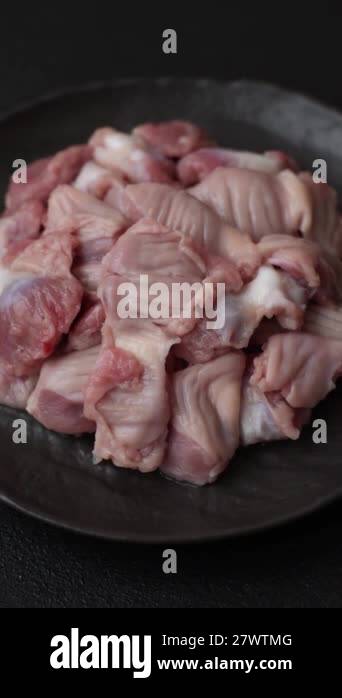 Raw chicken or turkey stomach with salt, spices and herbs on a textured ...
