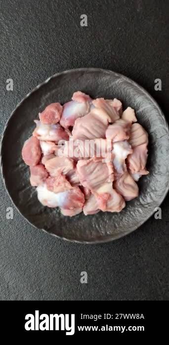 Raw chicken or turkey stomach with salt, spices and herbs on a textured ...
