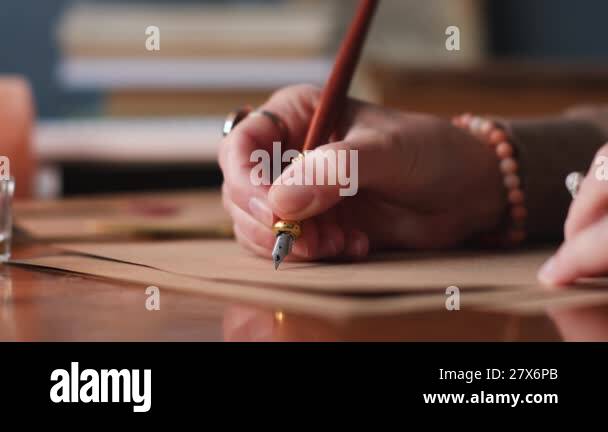 young woman writes a letter with an ink pen. A woman writes a letter ...