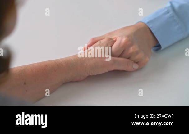 Close-up view of young female hands holding old grandma arm at table ...