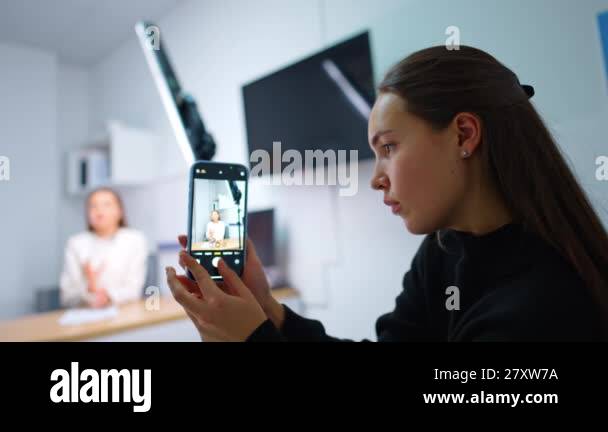 Caucasian brunette woman taking video and photo of a lady speaking at ...