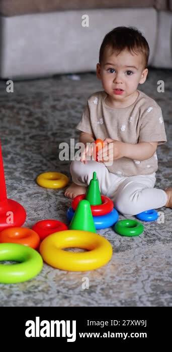 Little barefoot boy sits on the carpet surrounded by toys. Caucasian ...
