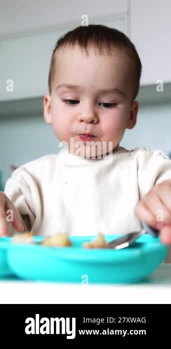 Little kid eating from plate using spoon. Baby is growing , developing ...