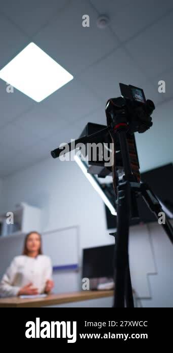Modern camera on tripod recording a video. Unrecognized female sitting ...