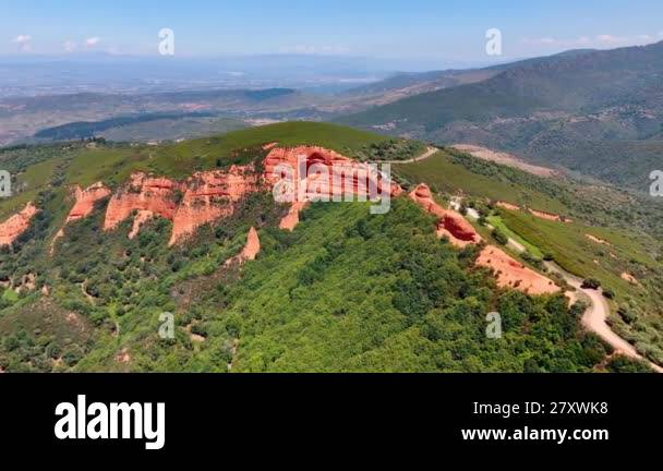 Green mountains with red rock formations sticking out from greenery ...