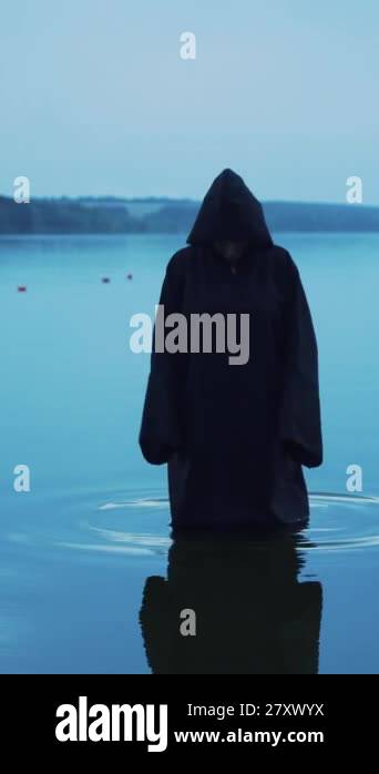 Evil witch in black cloak with hood in the river. Halloween costume ...